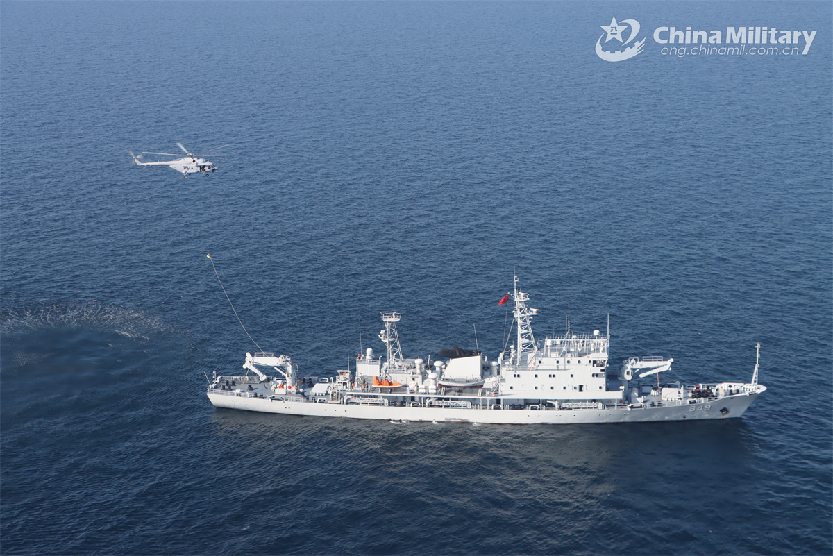 Naval ship and air force helicopter in joint search and rescue training